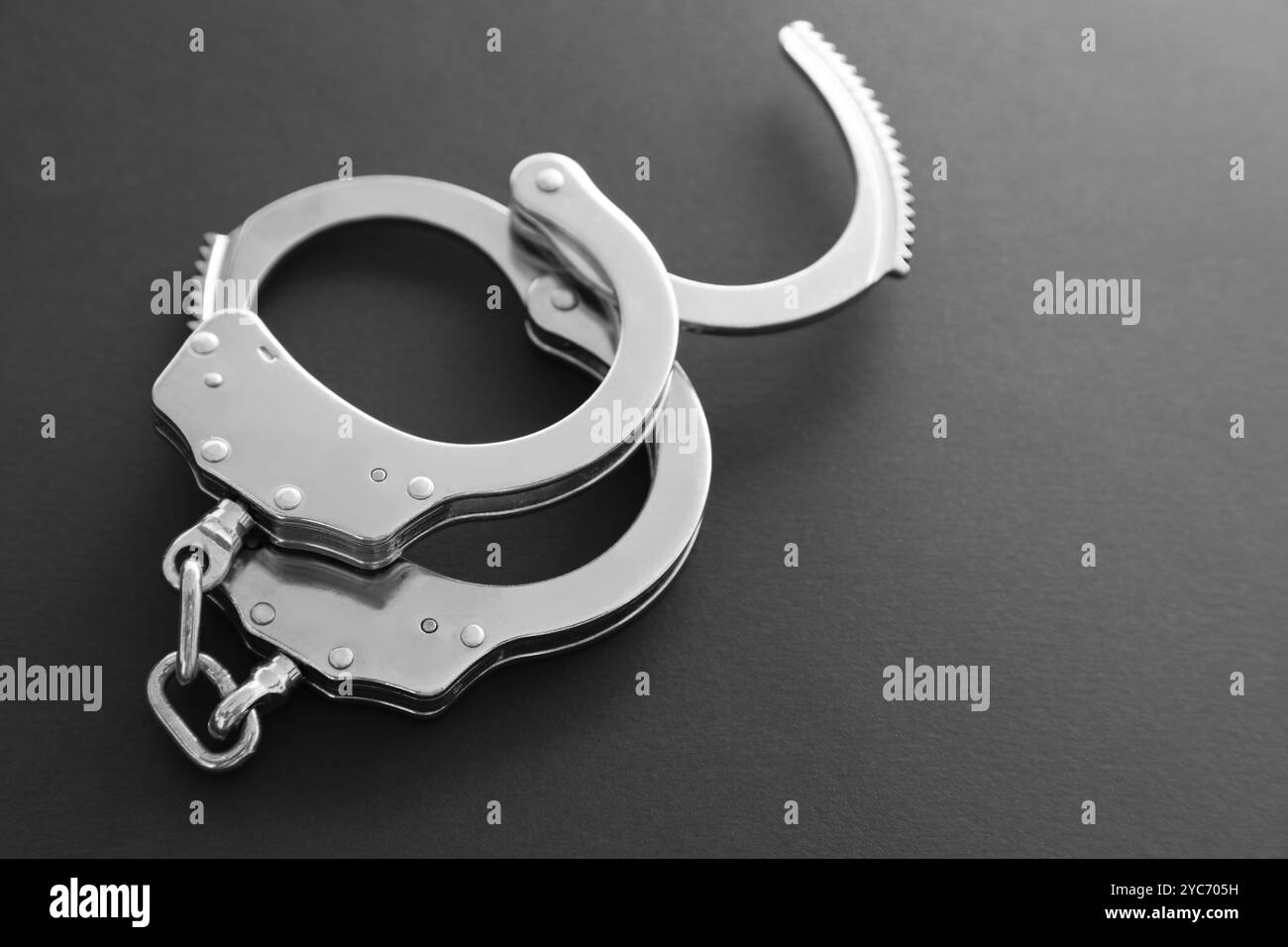 Classic chain handcuffs on black background, closeup. Space for text ...