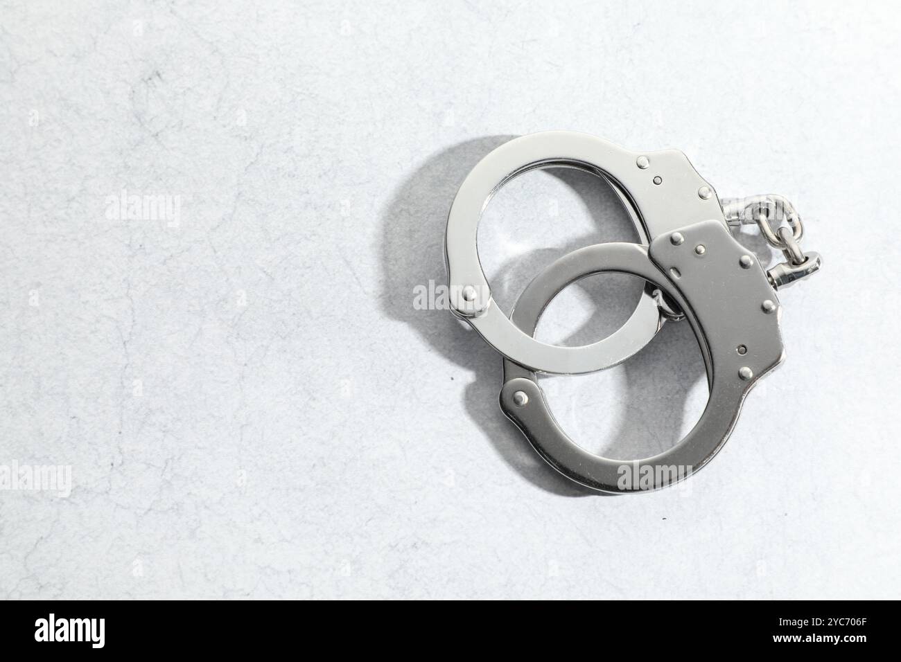 Metal chain handcuffs on light grey table, top view. Space for text ...