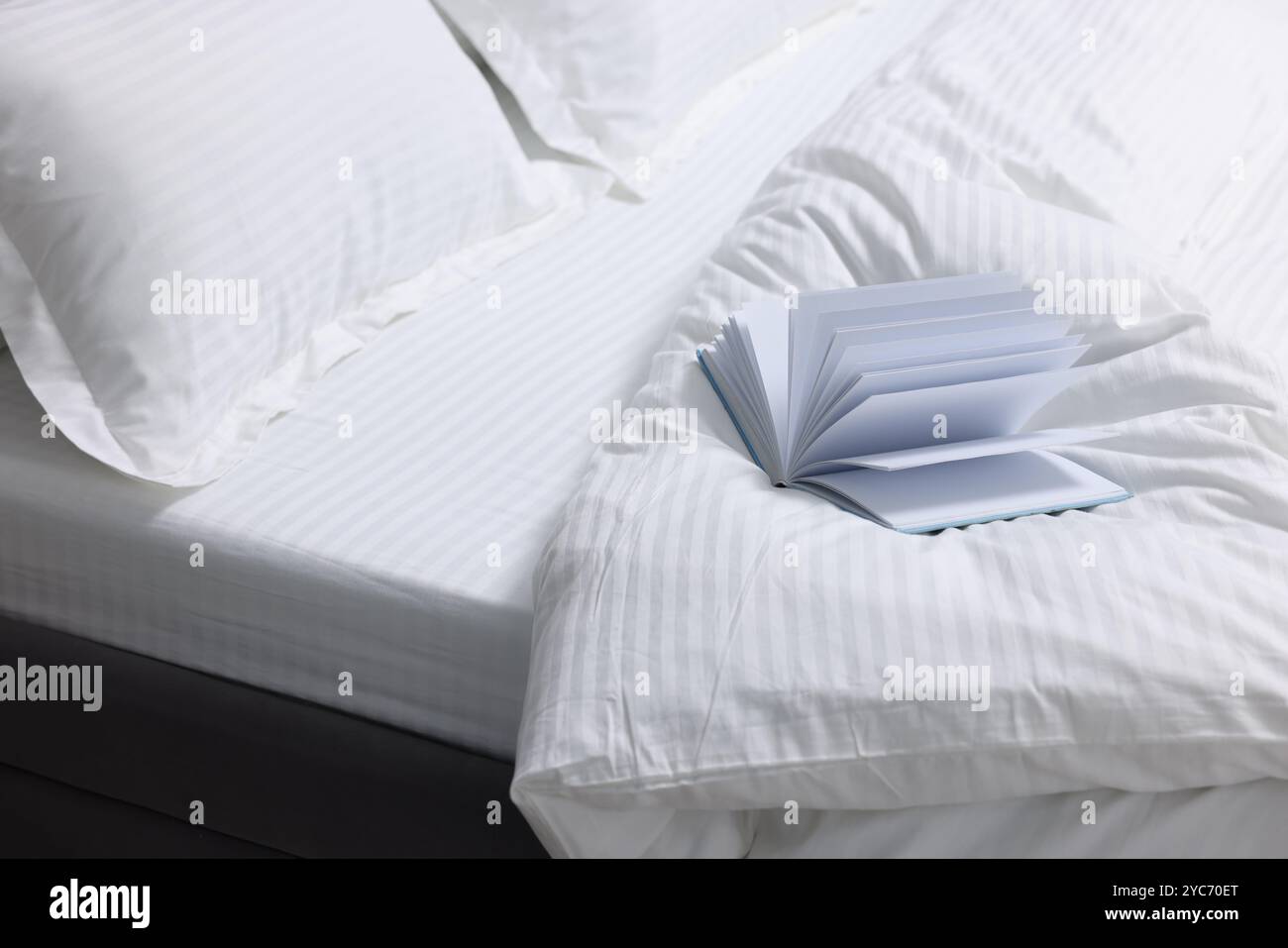Open book on bed with clean linens indoors Stock Photo - Alamy