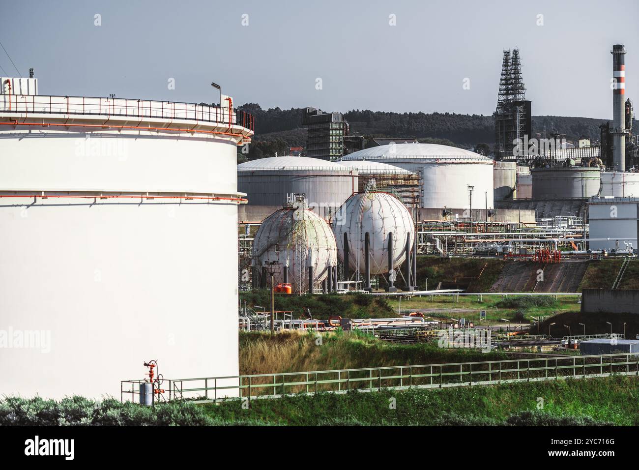 Industrial oil refinery with large white storage tanks, spherical gas ...