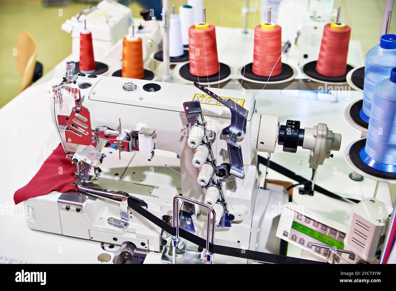 Spools of thread and sewing coverstitch machine. Collarette attaching ...