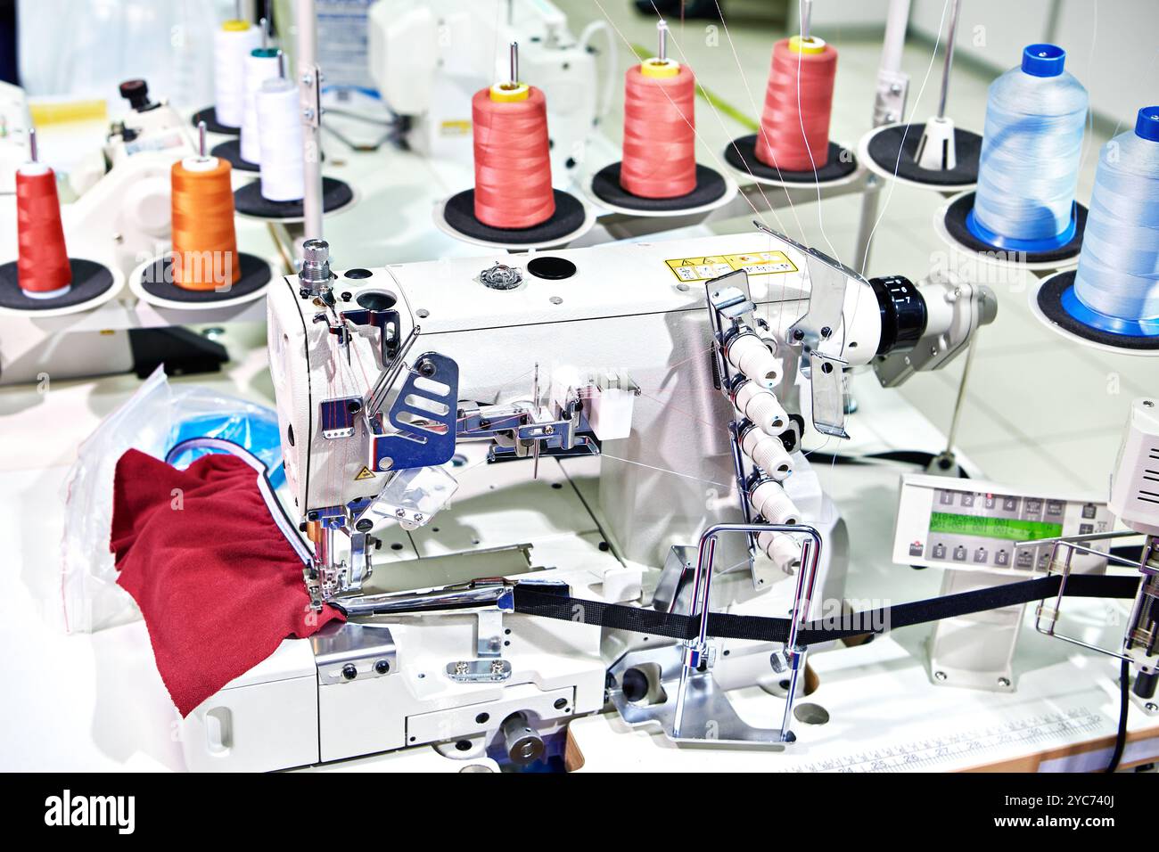 Spools of thread and sewing coverstitch machine. Collarette attaching ...