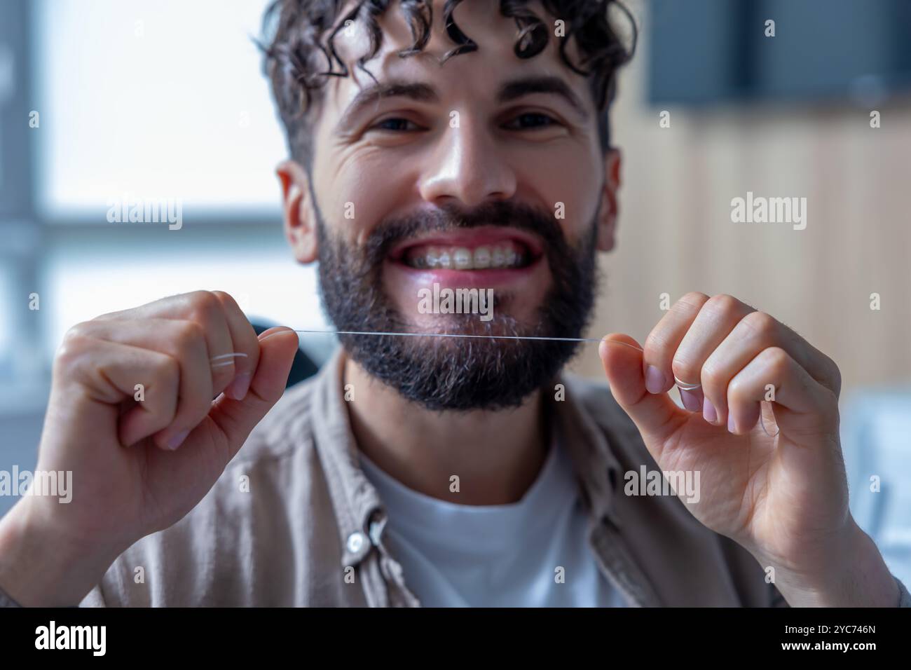 Bearded man carefully flossing his teeth and braces doing hygienic morning routine Stock Photo ...