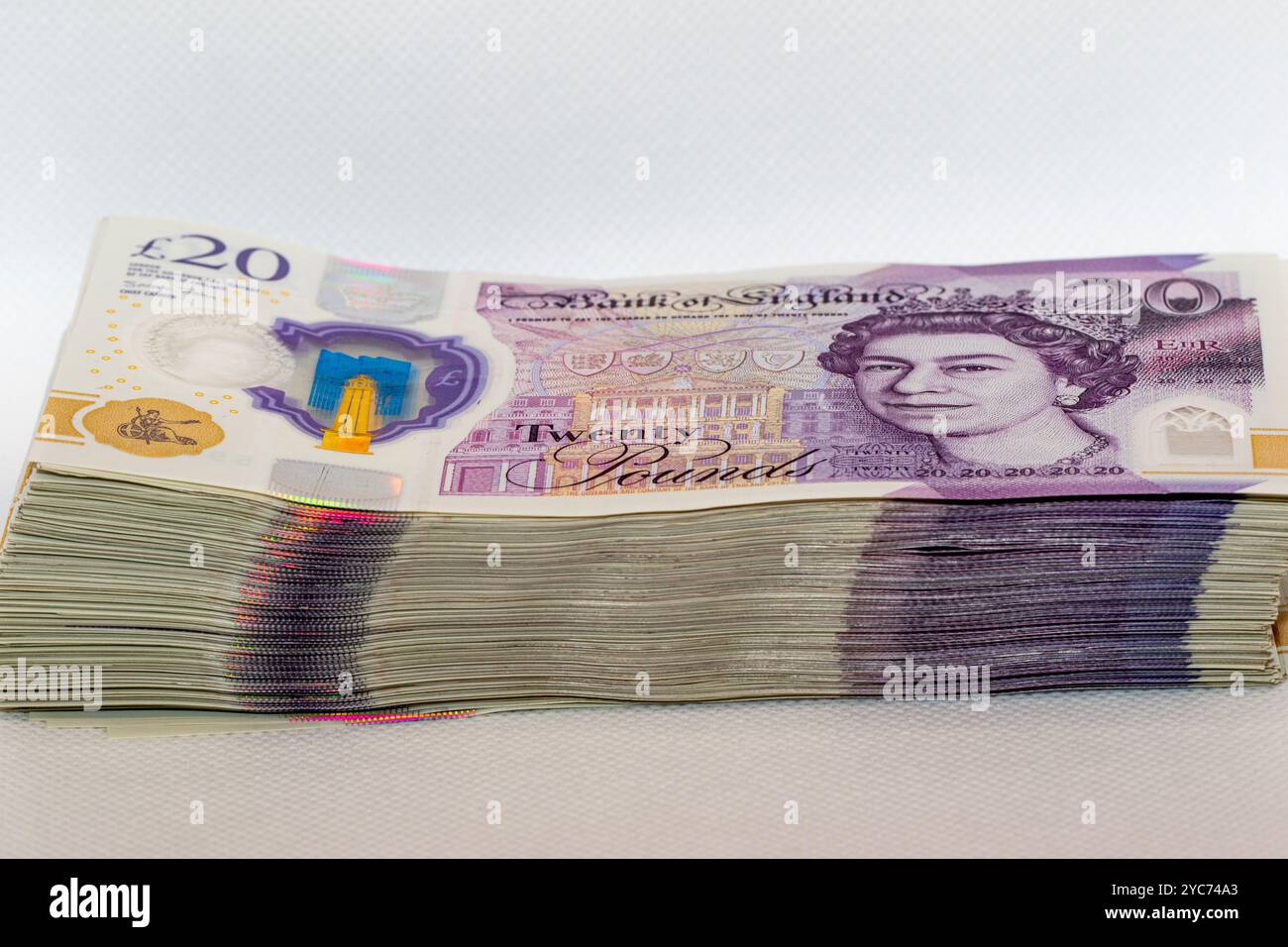 A neatly stacked pile of British twenty pound banknotes, featuring ...