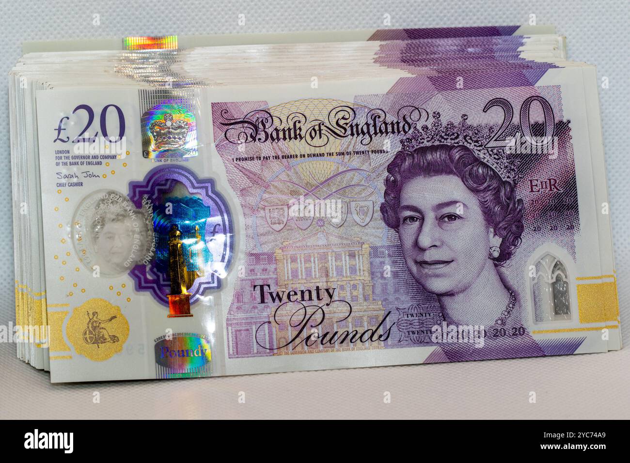 Stack of British 20-pound banknotes with security features visible ...