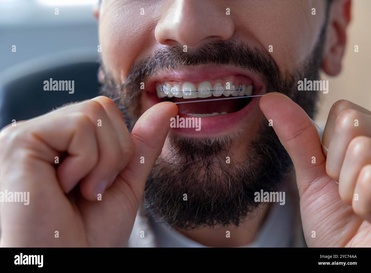 Bearded man carefully flossing his teeth and braces doing hygienic morning routine Stock Photo ...