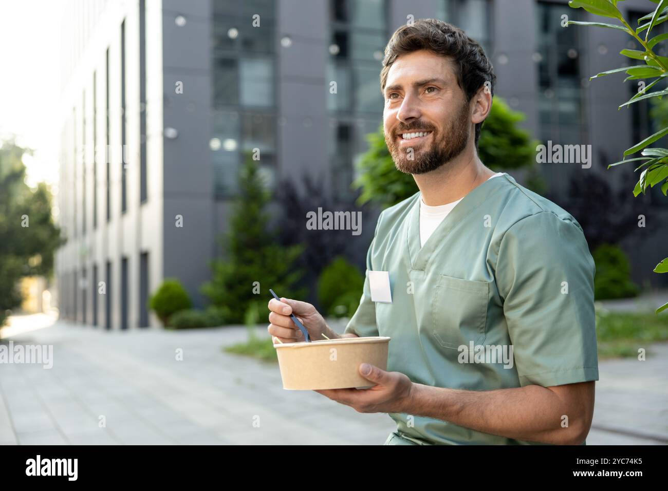 Man doctor having healthy lunch snack in front of hospital building ...