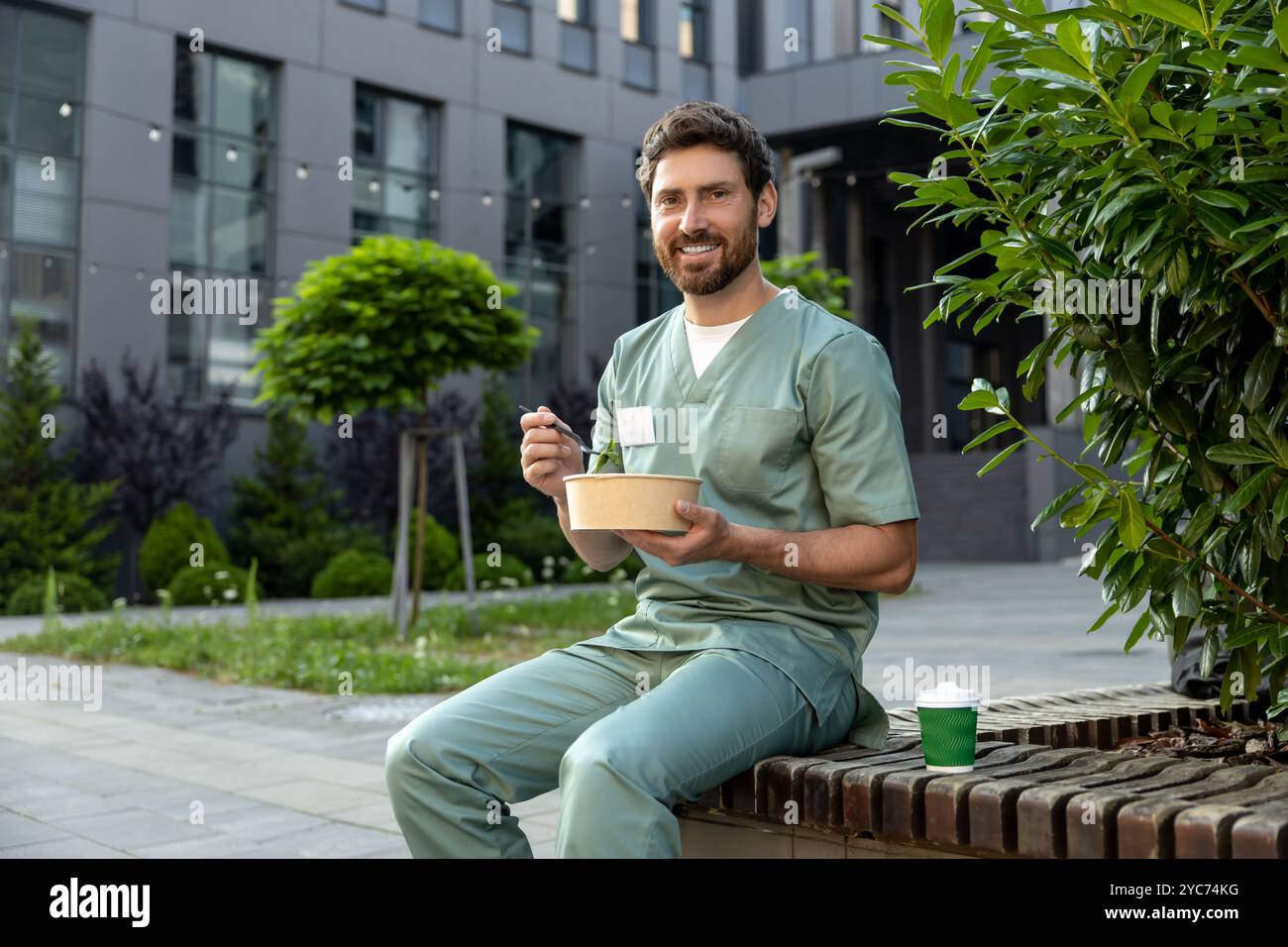 Doctor in scrubs takes lunch break outdoors sitting on bench near ...
