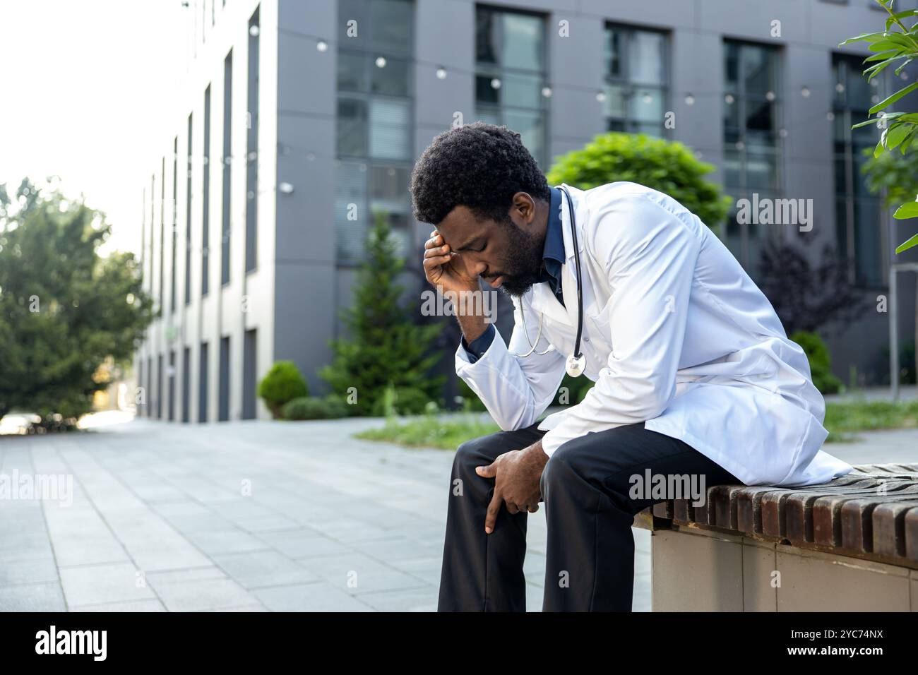 Stressed tired medical practitioner man sitting outside near clinic ...