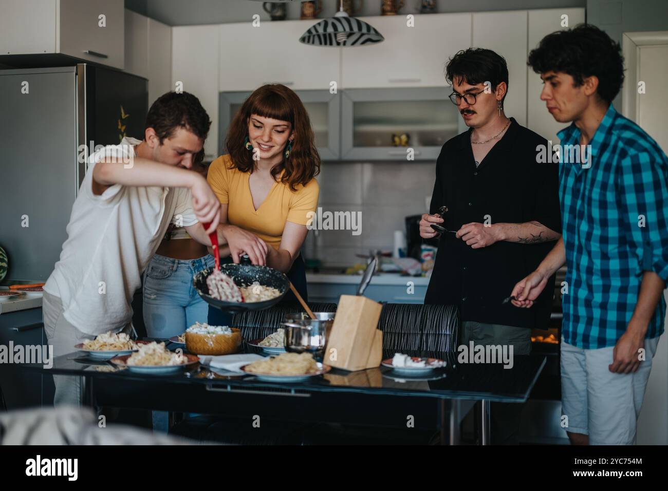 Friends serving pasta meal in kitchen while bonding together Stock ...