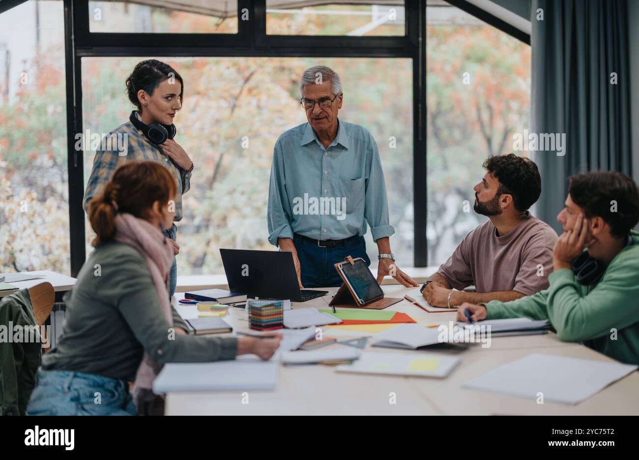 University students collaborating with senior professor for project ...