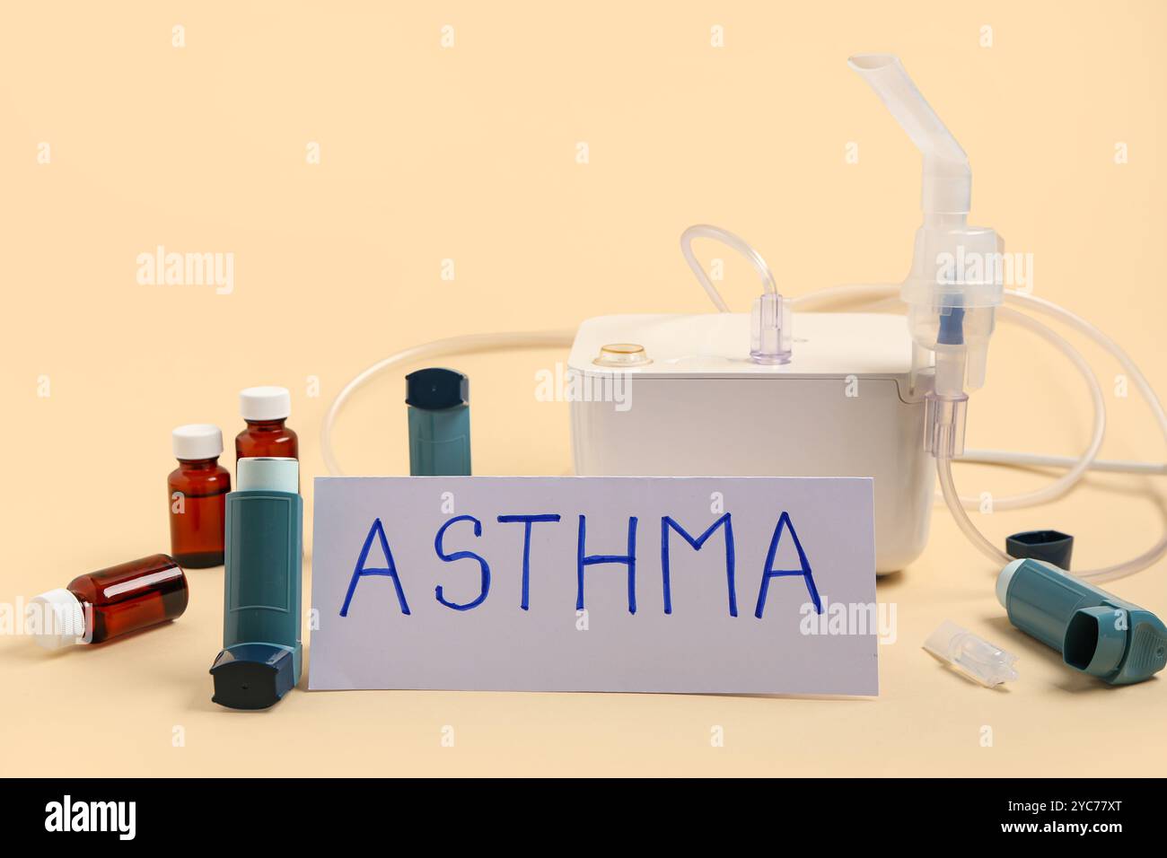 Modern inhalers with bottles of medicines and word ASTHMA on beige ...