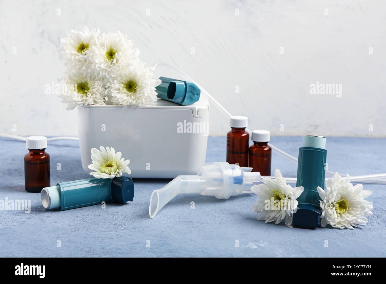 Modern nebulizer with inhalers and chrysanthemum flowers on blue grunge ...