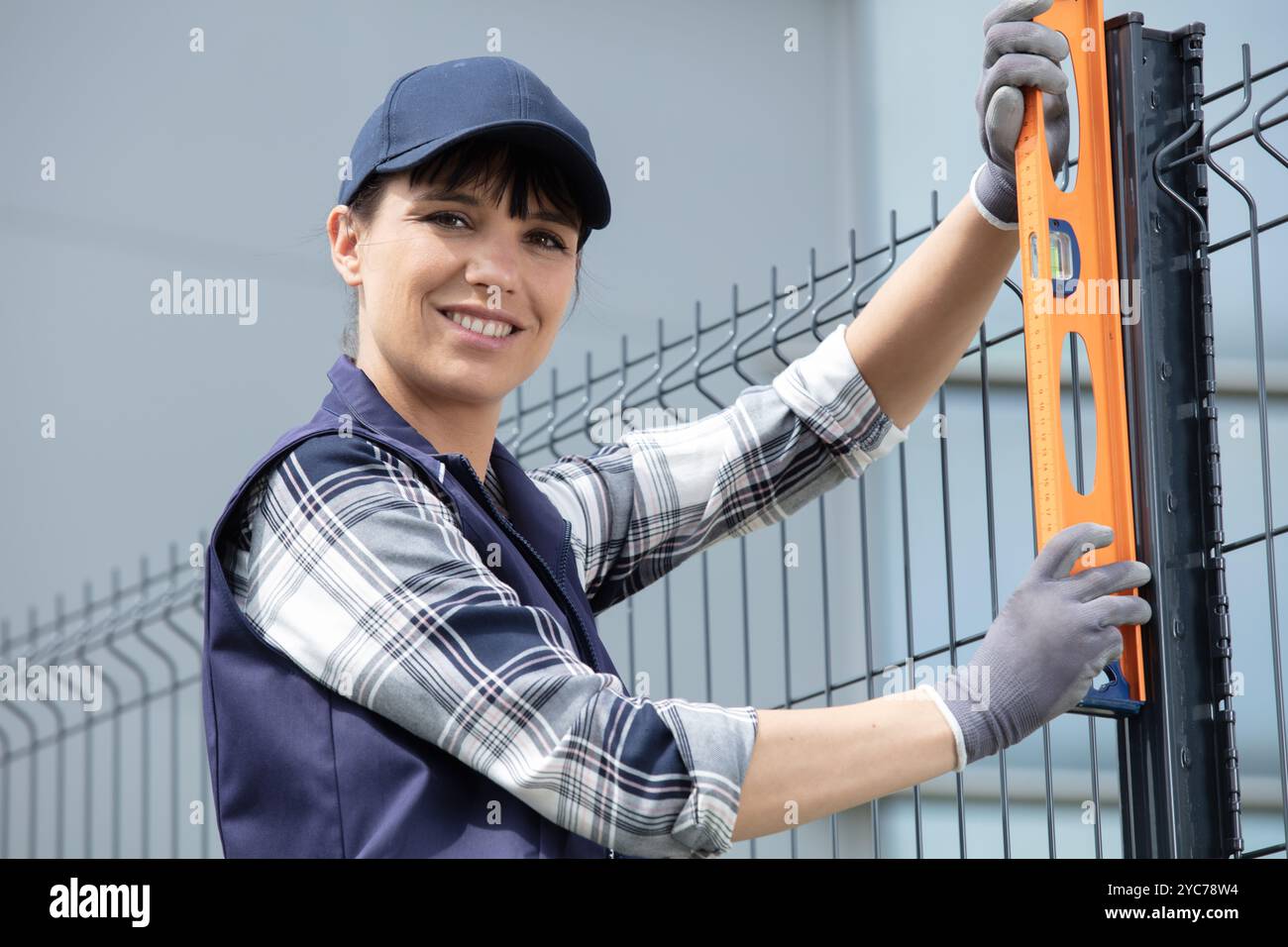 woman building metal fence checking regularly with a spirit level Stock ...