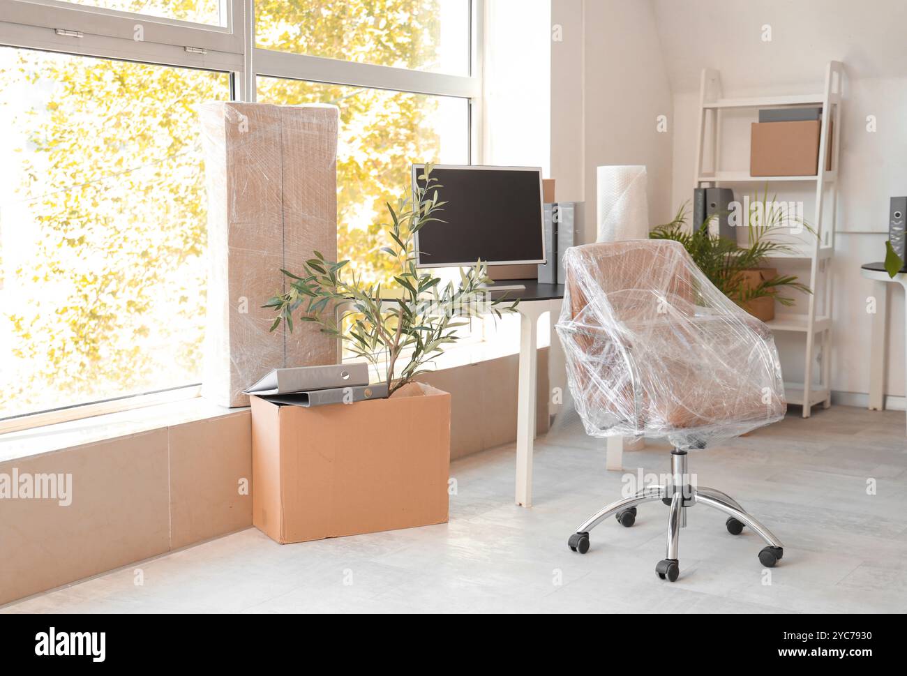 Workplace with wrapped chair and cardboard boxes in office on moving ...