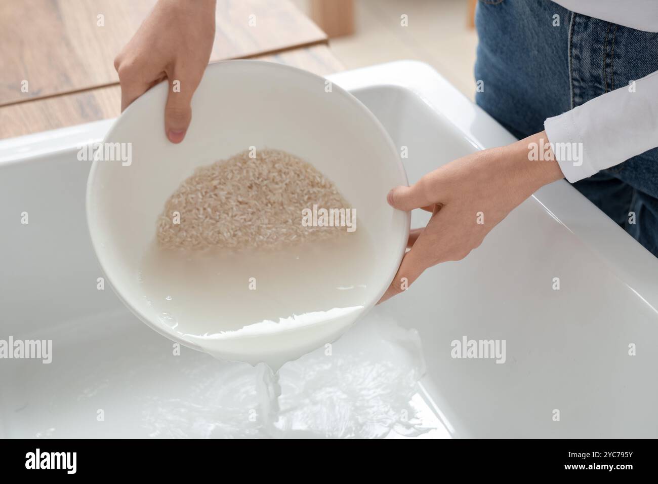 Woman pouring water into sink after rinsing rice, closeup Stock Photo ...