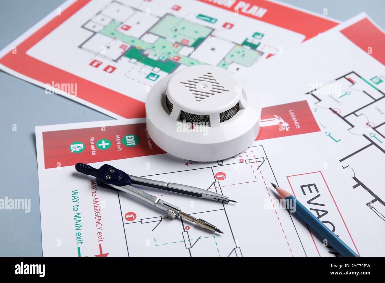 Modern smoke detector with pair of compasses and evacuation plans on ...