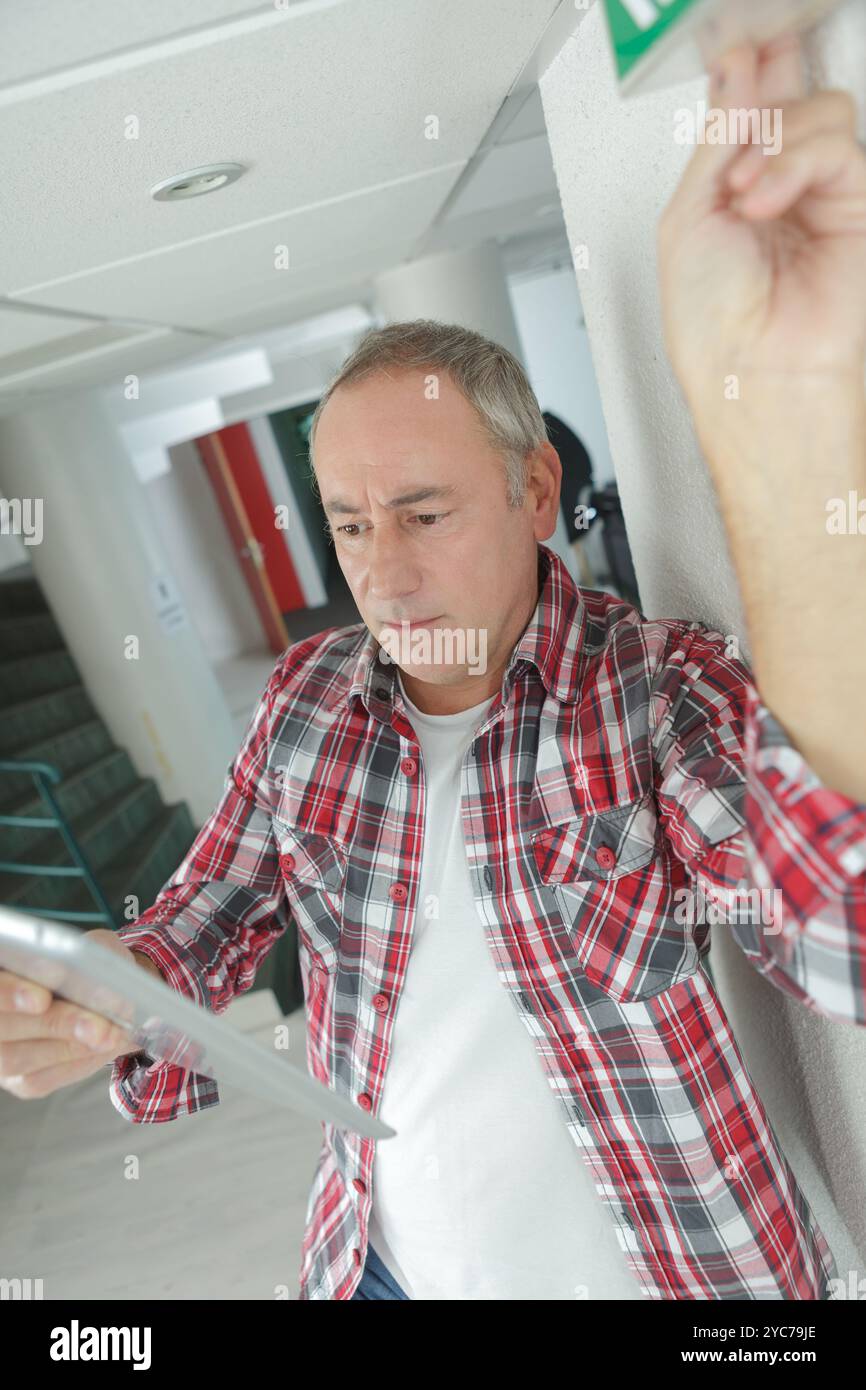 technician fixing the fire emergency exit sign Stock Photo - Alamy