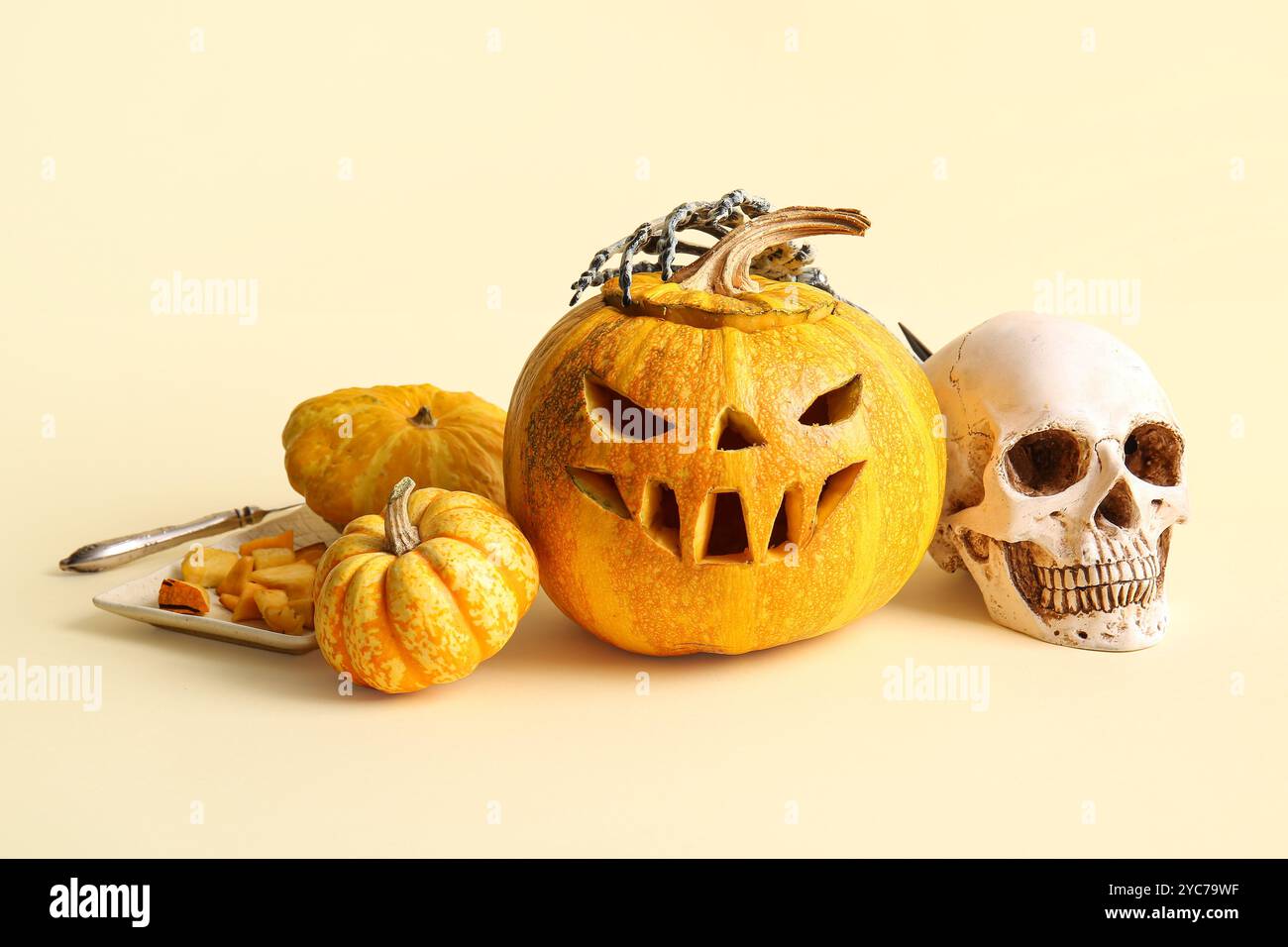 Halloween carved pumpkins with human skull and skeleton hand on beige ...