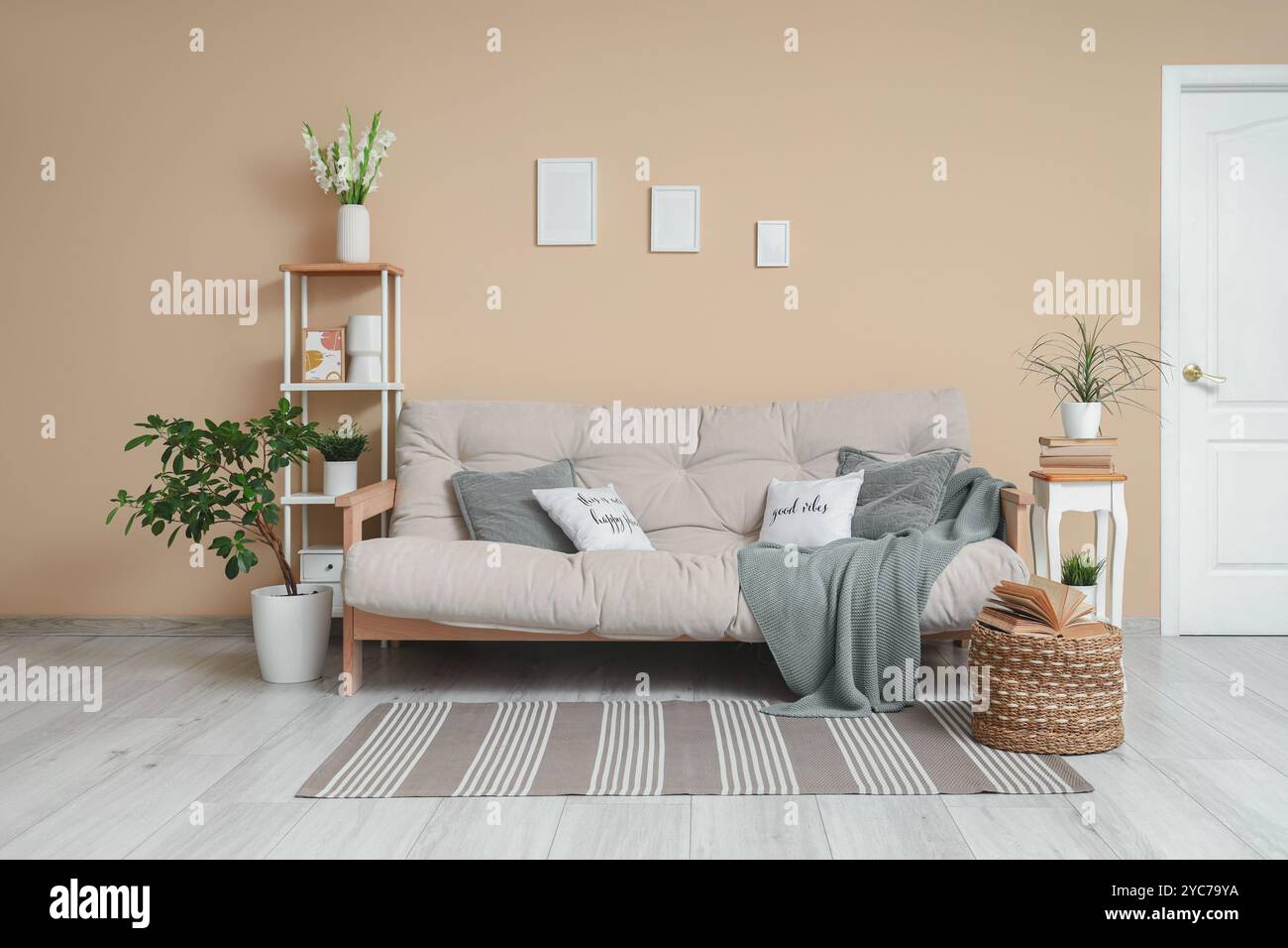 Sofa, decorated tree, shelving unit and pouf with book in interior of ...