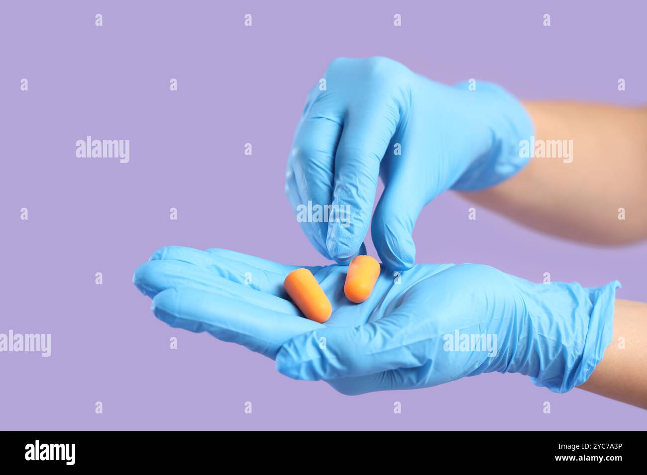 Female doctor with ear plugs on lilac background Stock Photo - Alamy