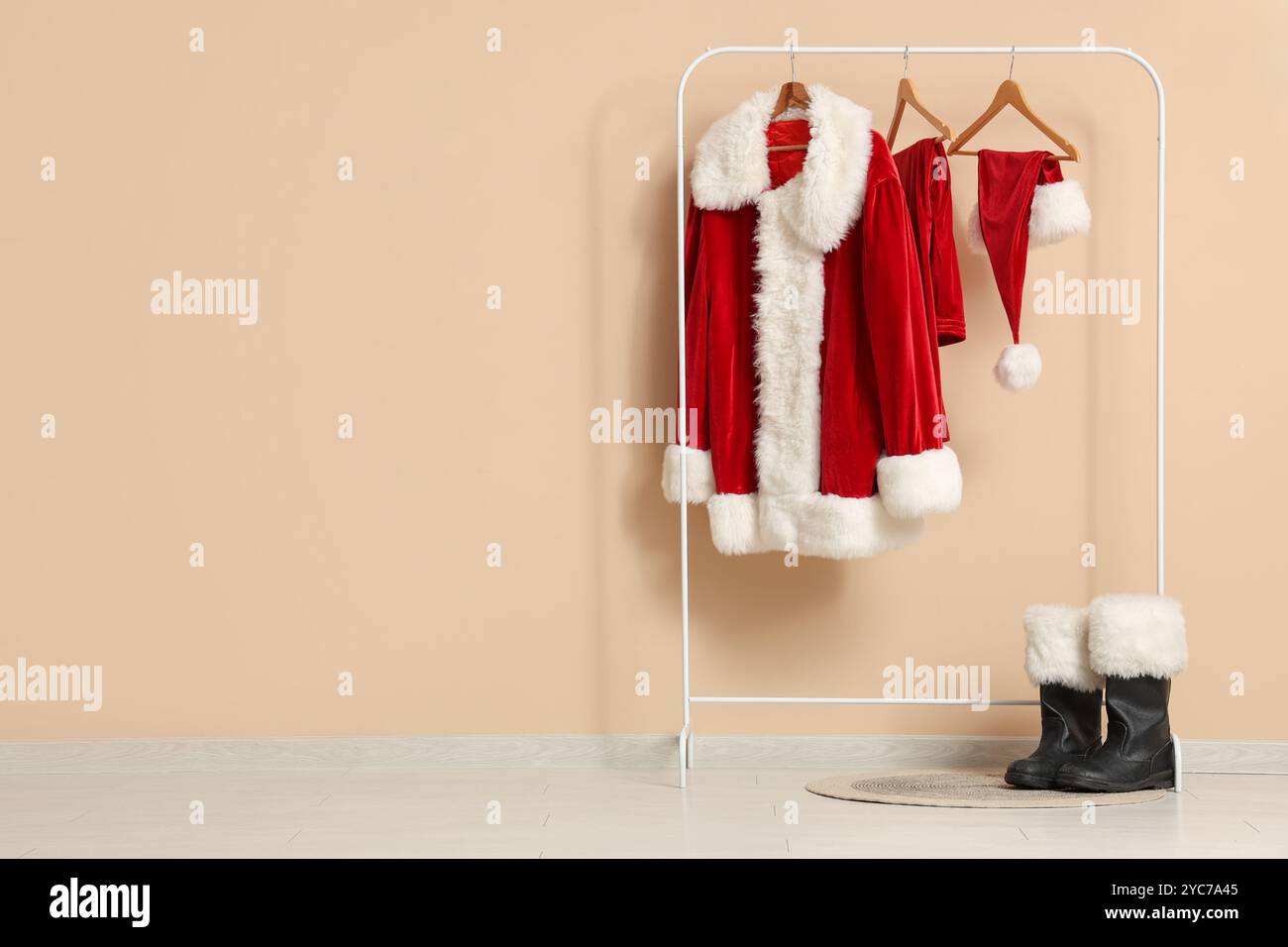Santa Claus suit hanging on rack near beige wall in room Stock Photo ...