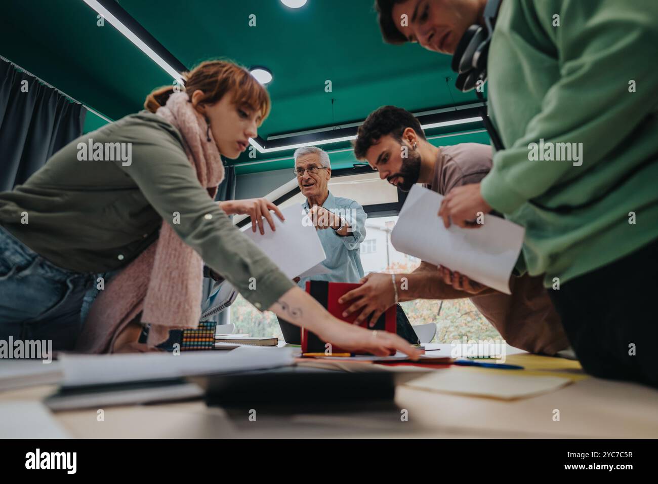 College students collaborating with guidance from elderly professor ...