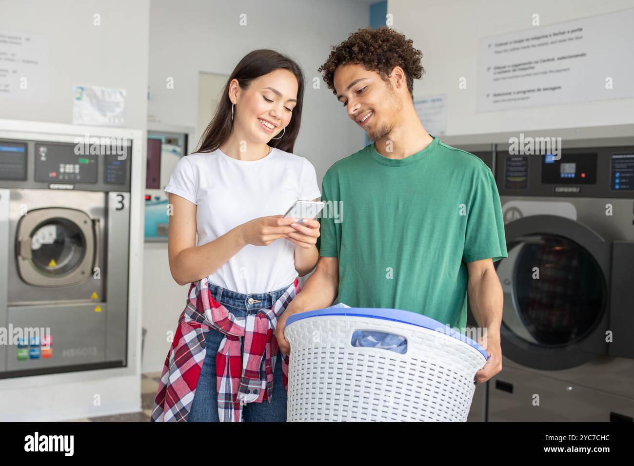 Young couple shares a moment in a laundromat while doing laundry ...