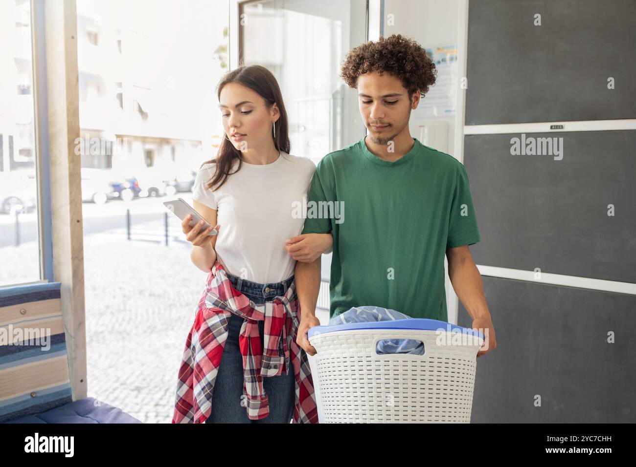 Couple helps each other while doing laundry in a modern laundromat ...