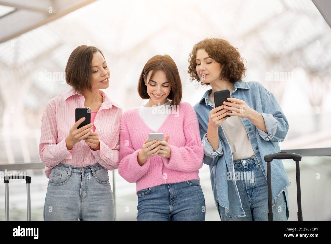 Three friends enjoying a moment together while checking their phones ...