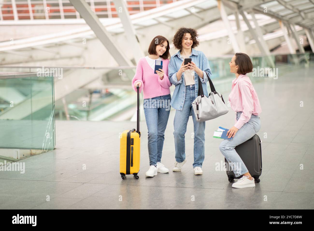 Three friends with luggage enjoying travel plans at an airport terminal ...