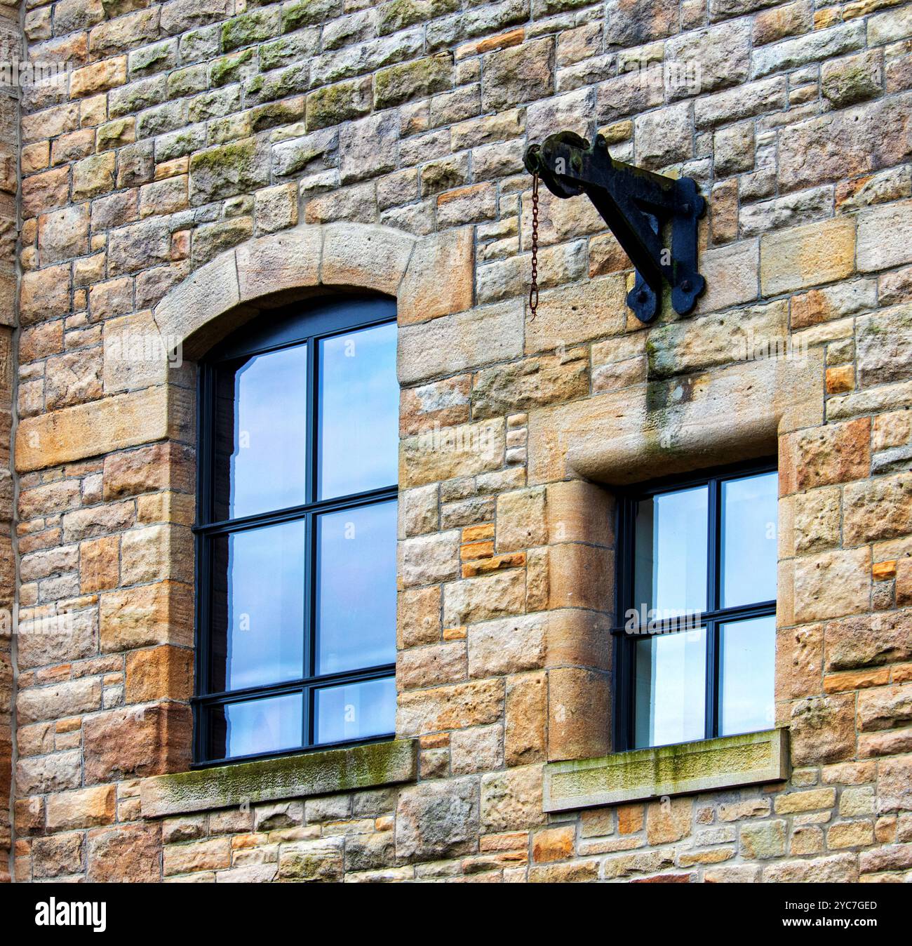 An abstract of an old hoist with a dangling chain, above a window on a ...