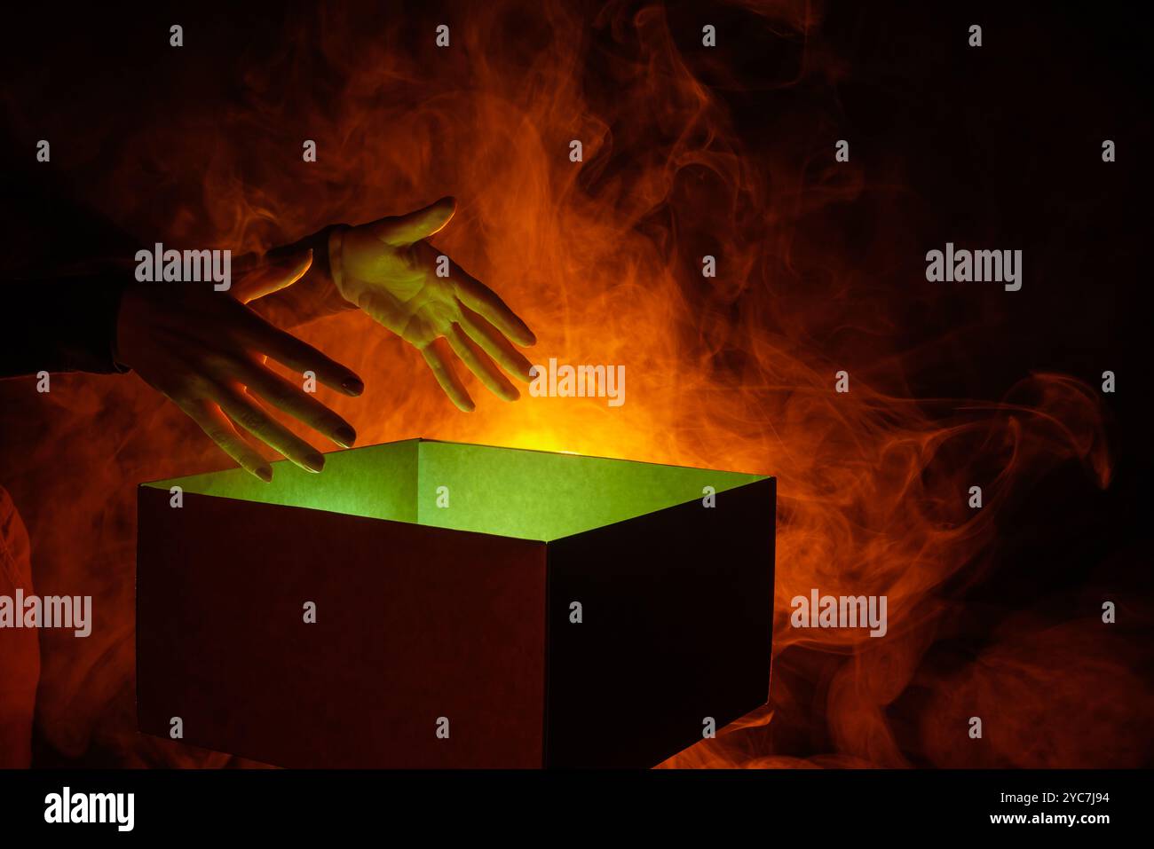 human hands taking out surprise from mysterious box on dark red ...