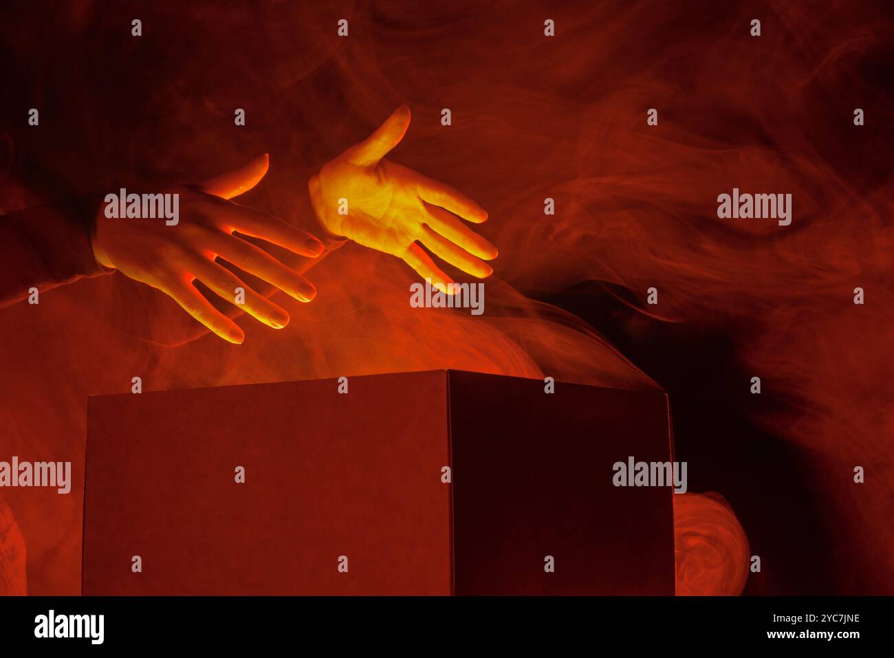 human hands taking out surprise from mysterious box on dark red ...