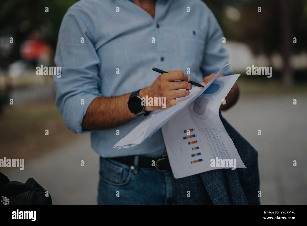 Business person taking notes on graphs in urban park setting Stock ...