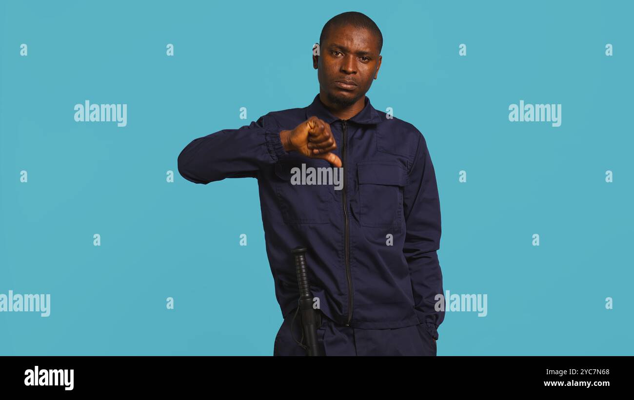 Portrait of security agent doing thumbs down sign gesturing, refusing ...