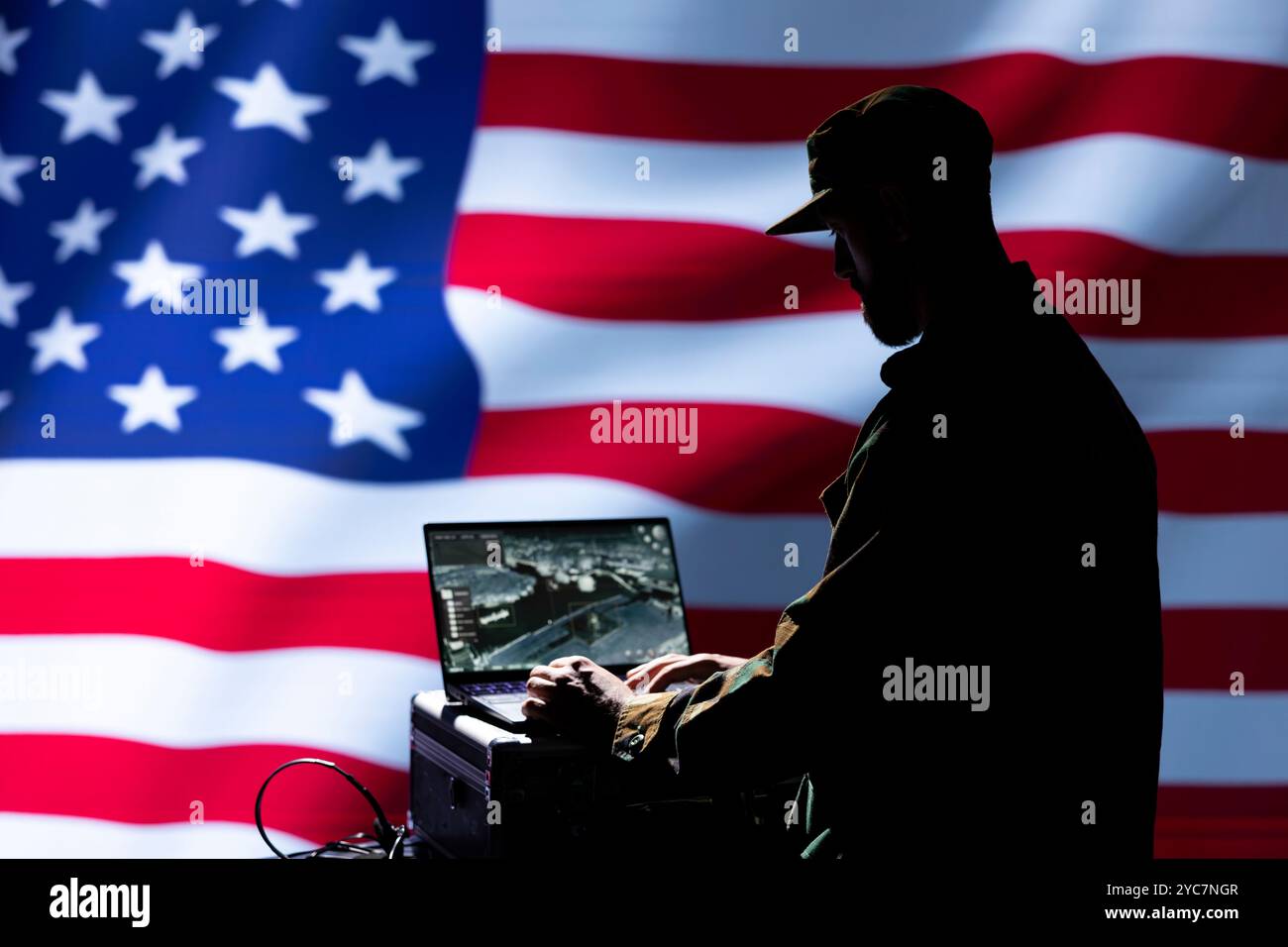 Military operative uses laptop to analyze surveillance data, standing ...