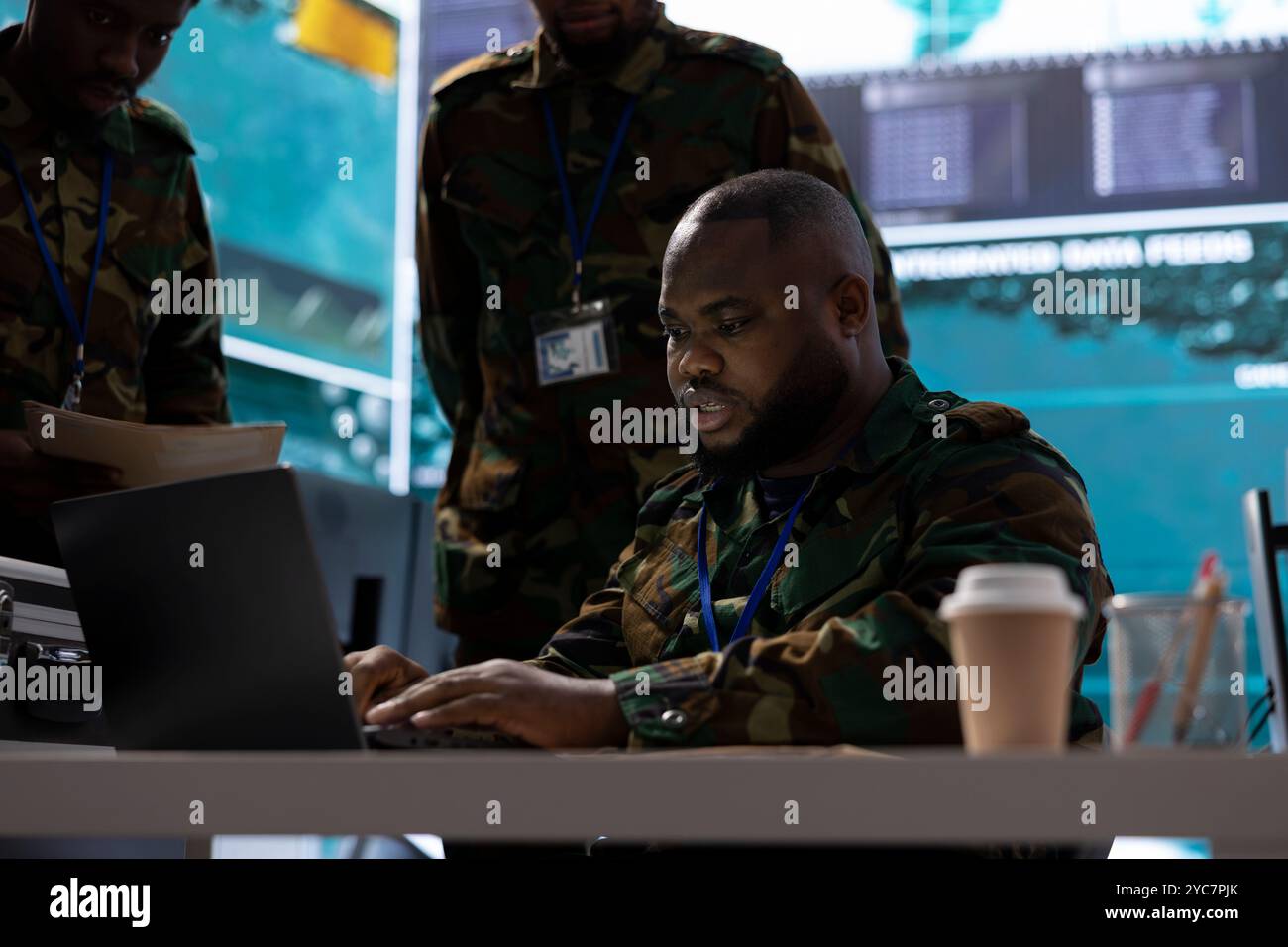 Soldiers analyzing and collecting real time data in a high tech military office, working on ...