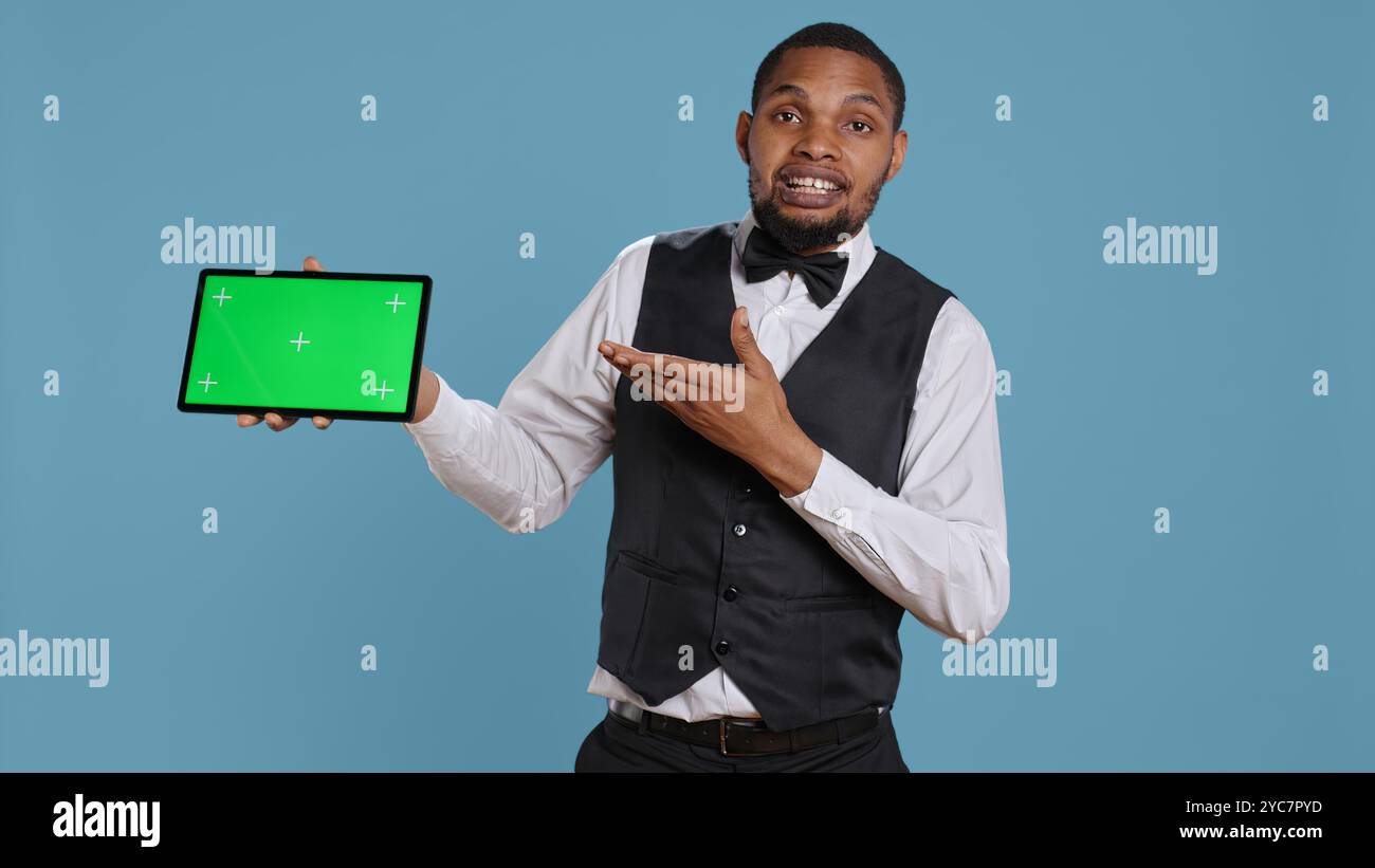 Doorkeeper bellboy poses with green screen on tablet at the hotel ...