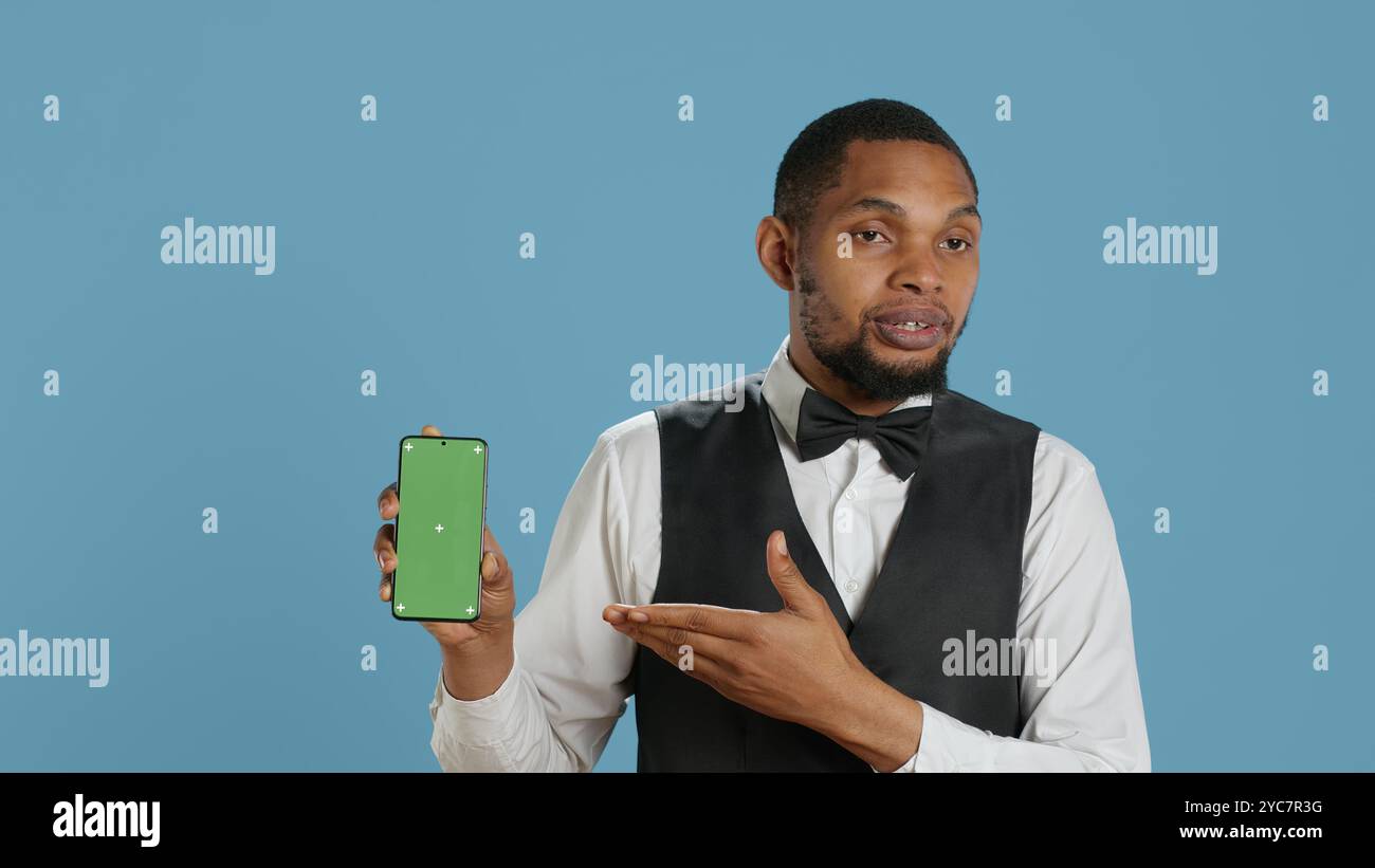 Hotel worker bellhop points at phone with isolated mockup display ...