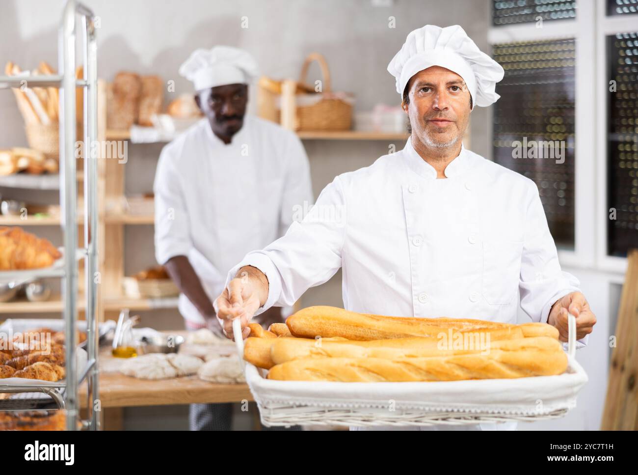 Professional baker presenting fresh french baguettes in bakery Stock ...