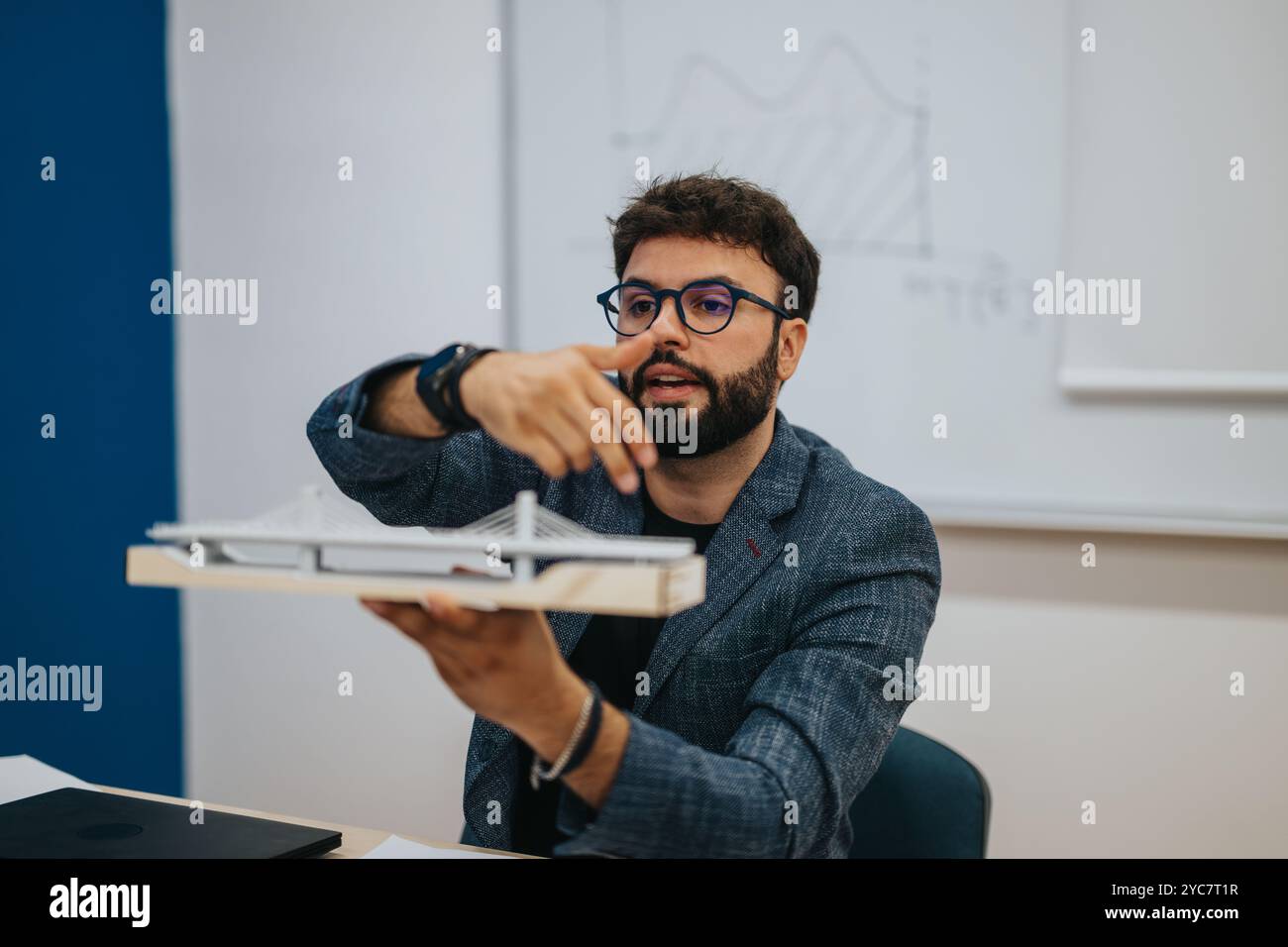 Teacher explaining architecture model in classroom setting to students ...