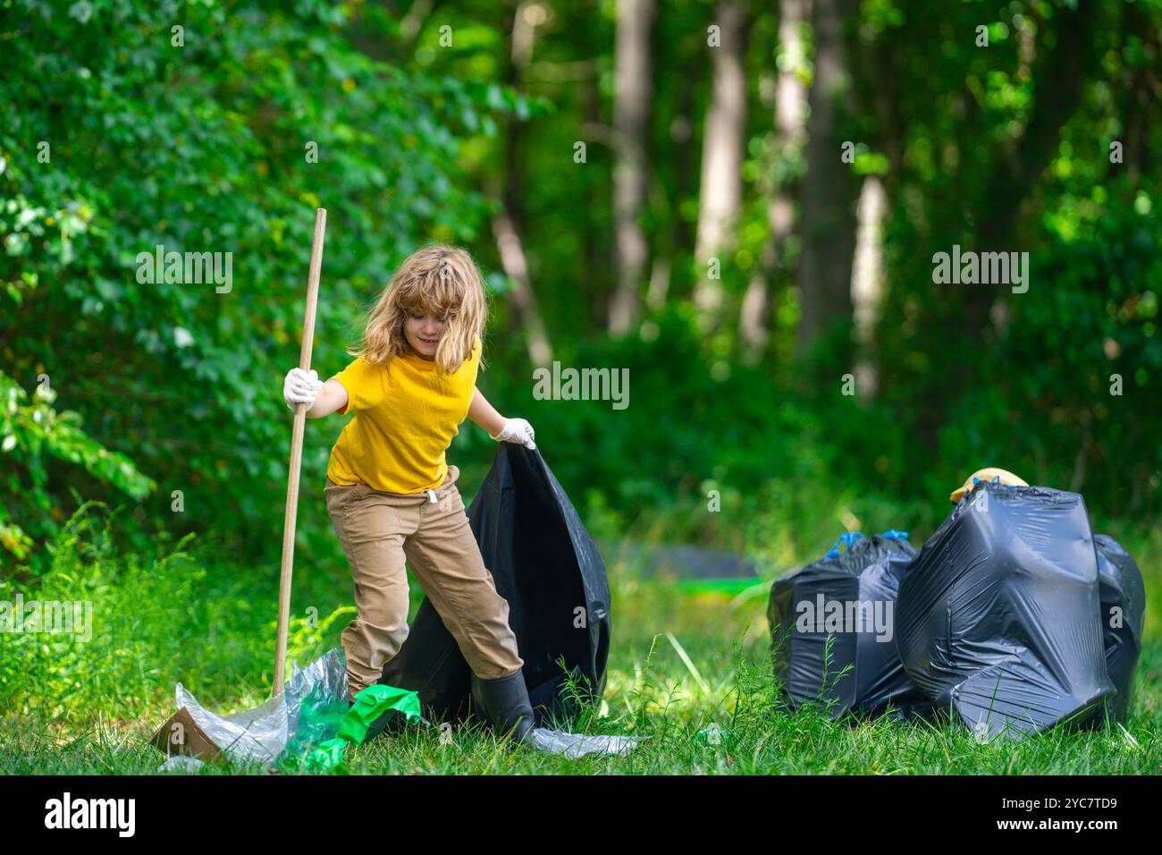 Kid cleaning up the park, putting trash in a garbage bag. Environmental ...