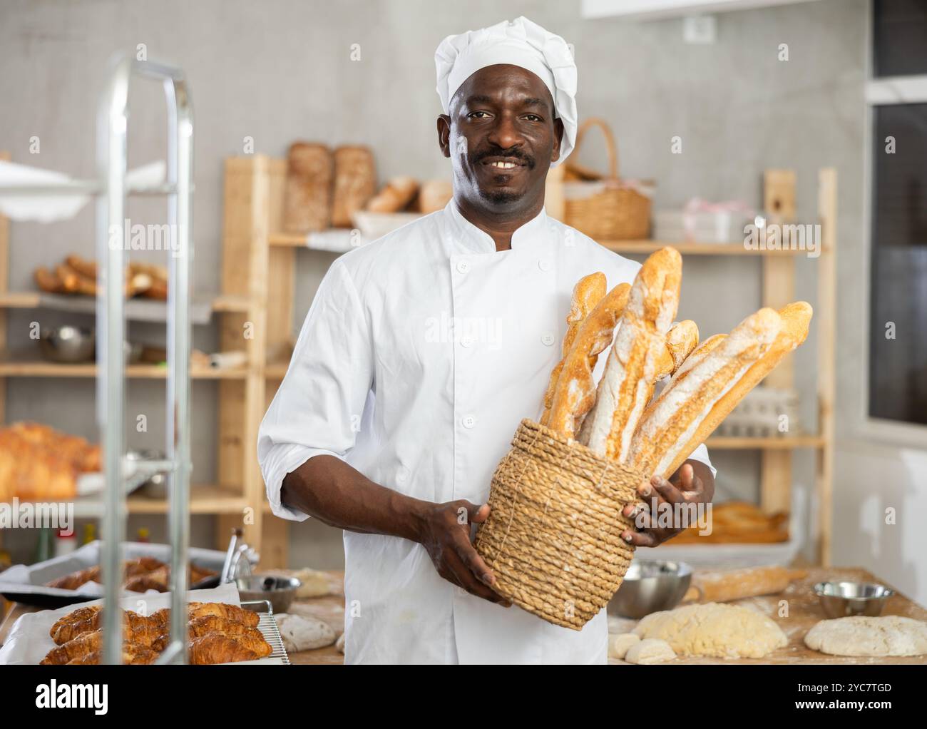 Successful African baker presenting golden baguettes in bakery Stock ...