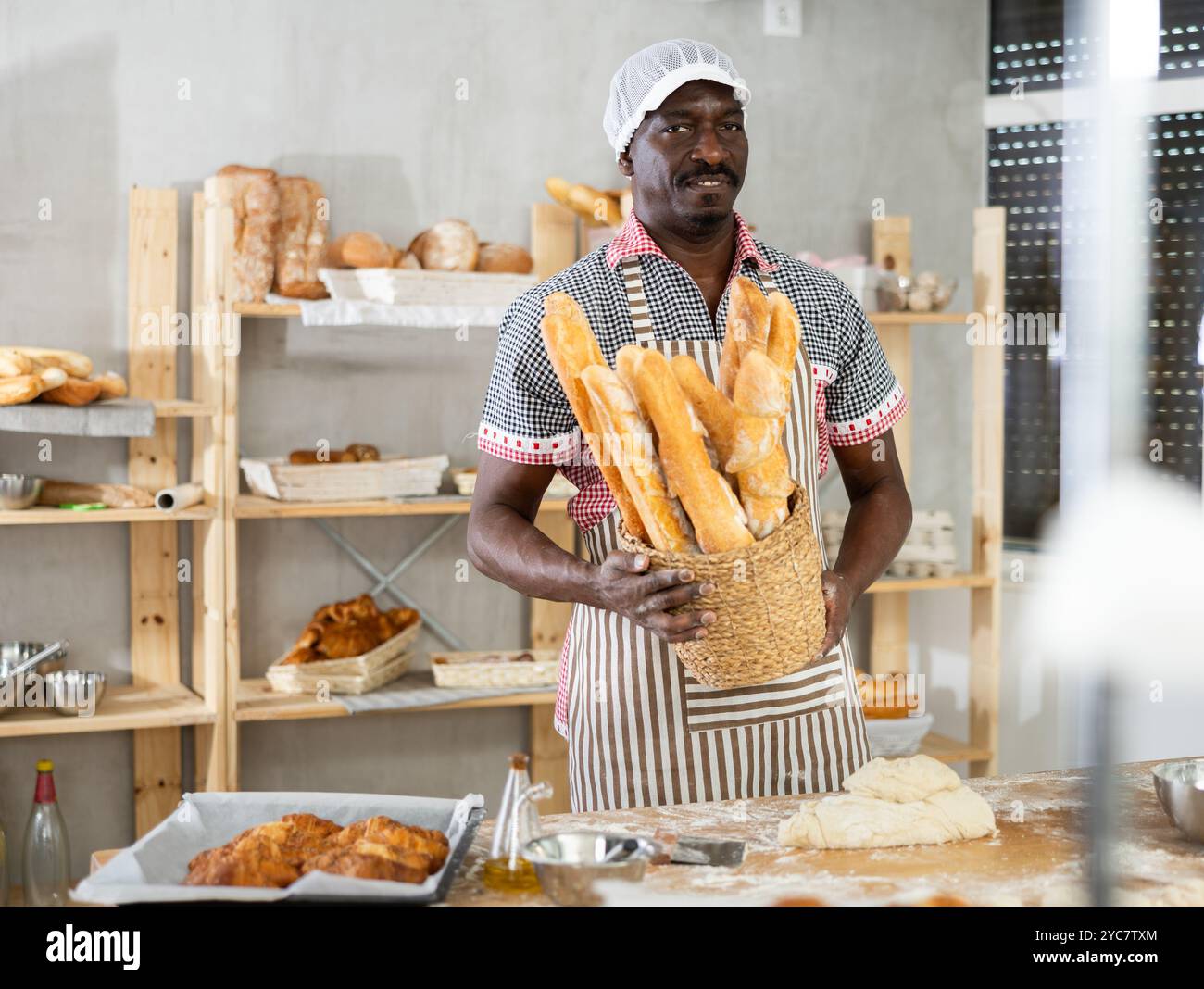 Successful African baker presenting golden baguettes in bakery Stock ...