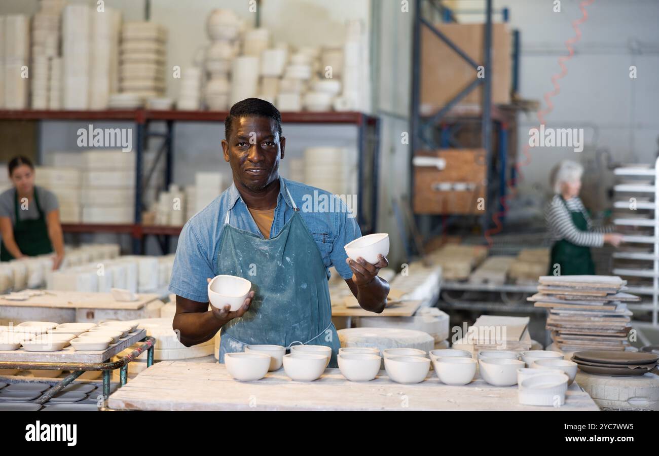 African american artisan having ceramics in hands and standing in ...