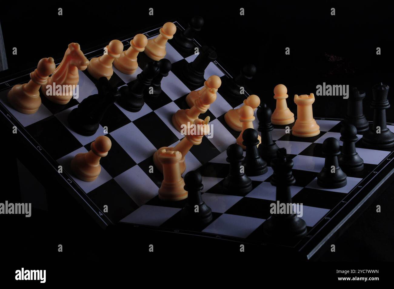 Chess game on tilted board with black and white pieces in dramatic ...