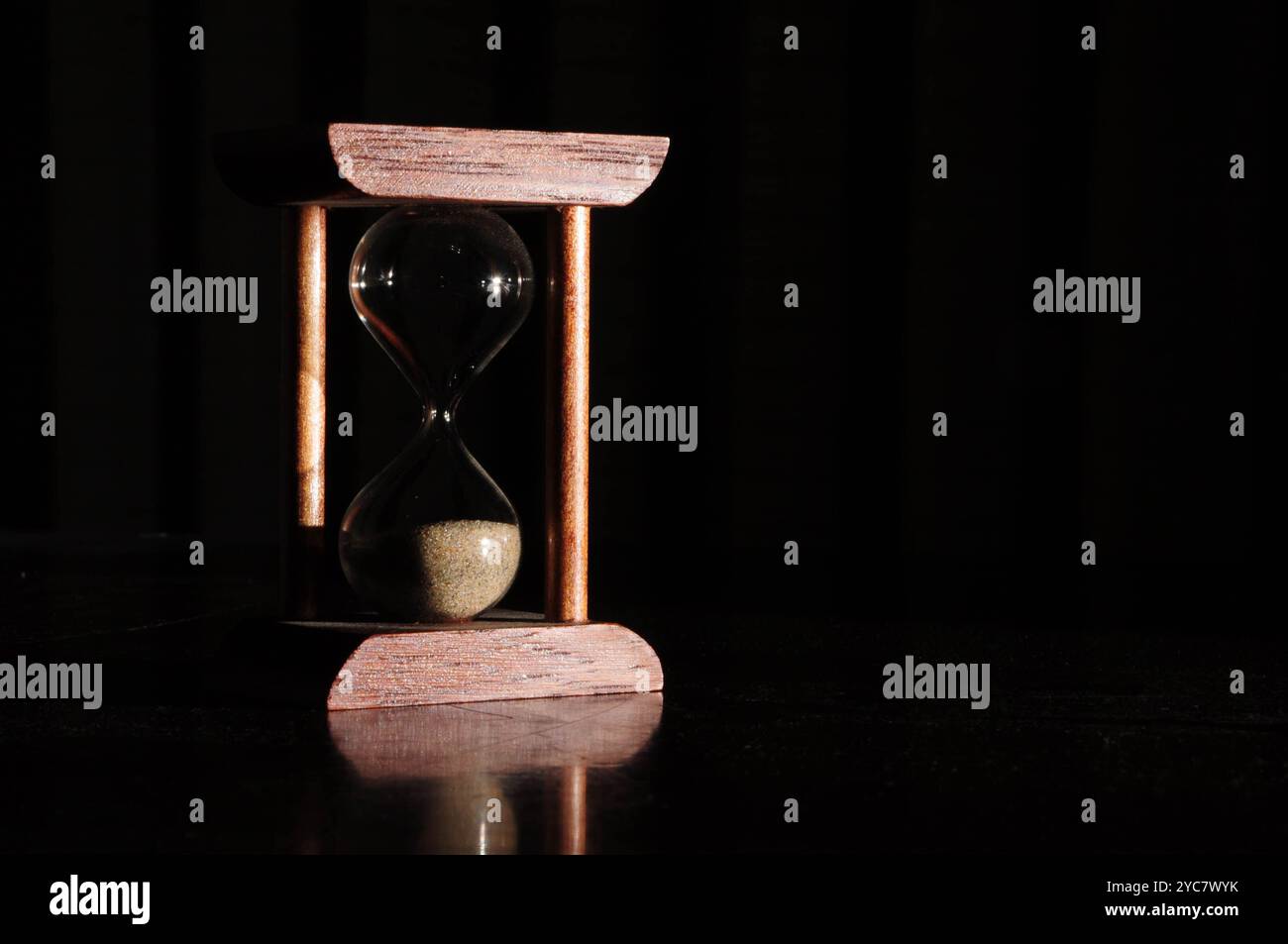 Classic wooden hourglass casting shadows, symbolizing time passage in ...