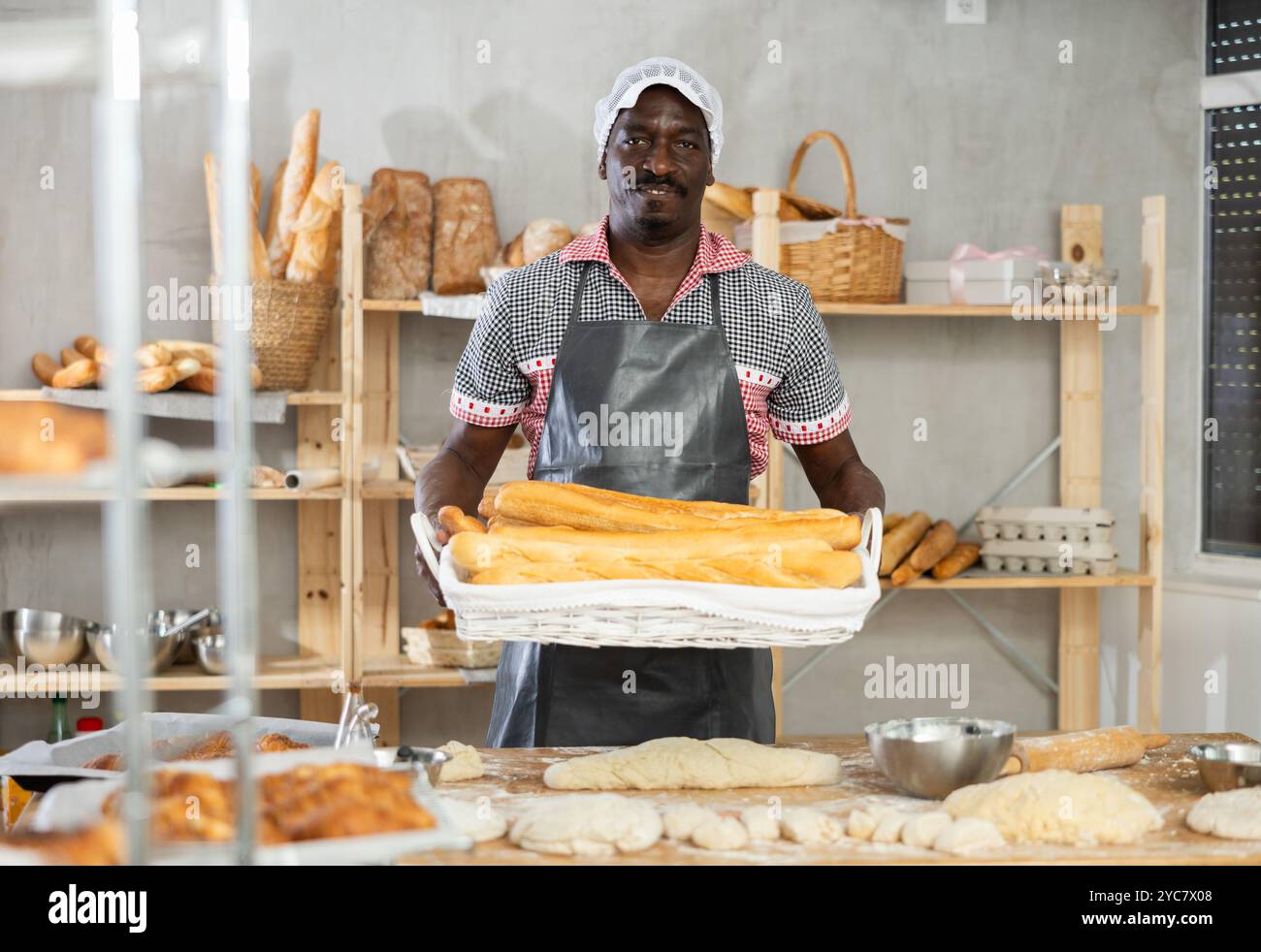 Successful African baker presenting golden baguettes in bakery Stock ...