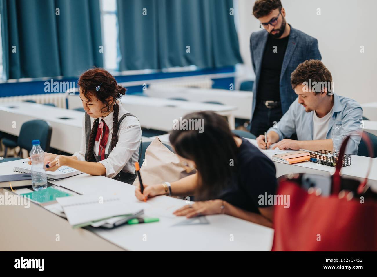 High school students studying with a teacher in a classroom setting ...